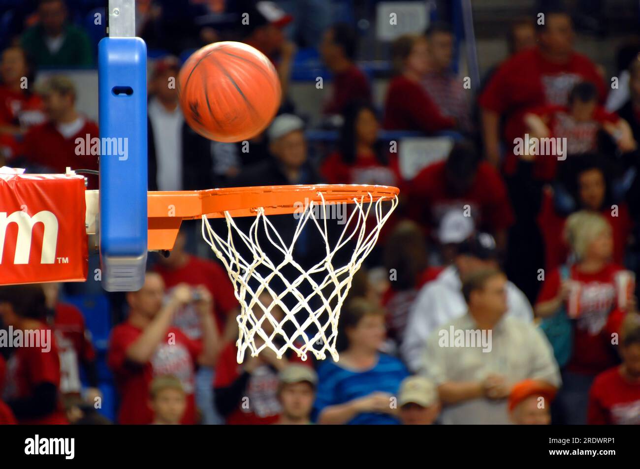 Spinning basketball uses the backboard to bounce into the goal. Crowded ...