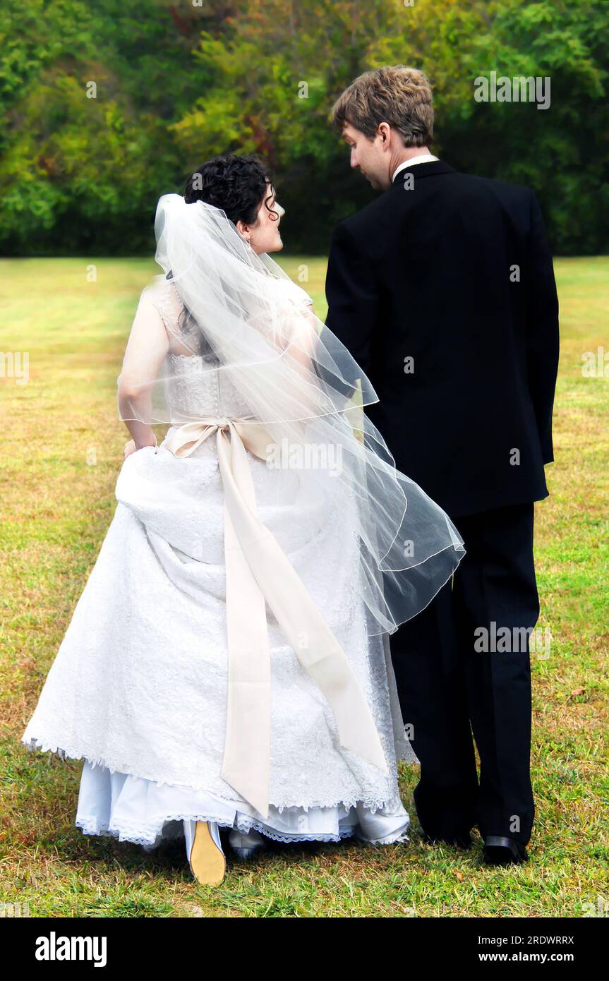 Bride and groom walk hand-in-hand outdoors after wedding ceremony ...