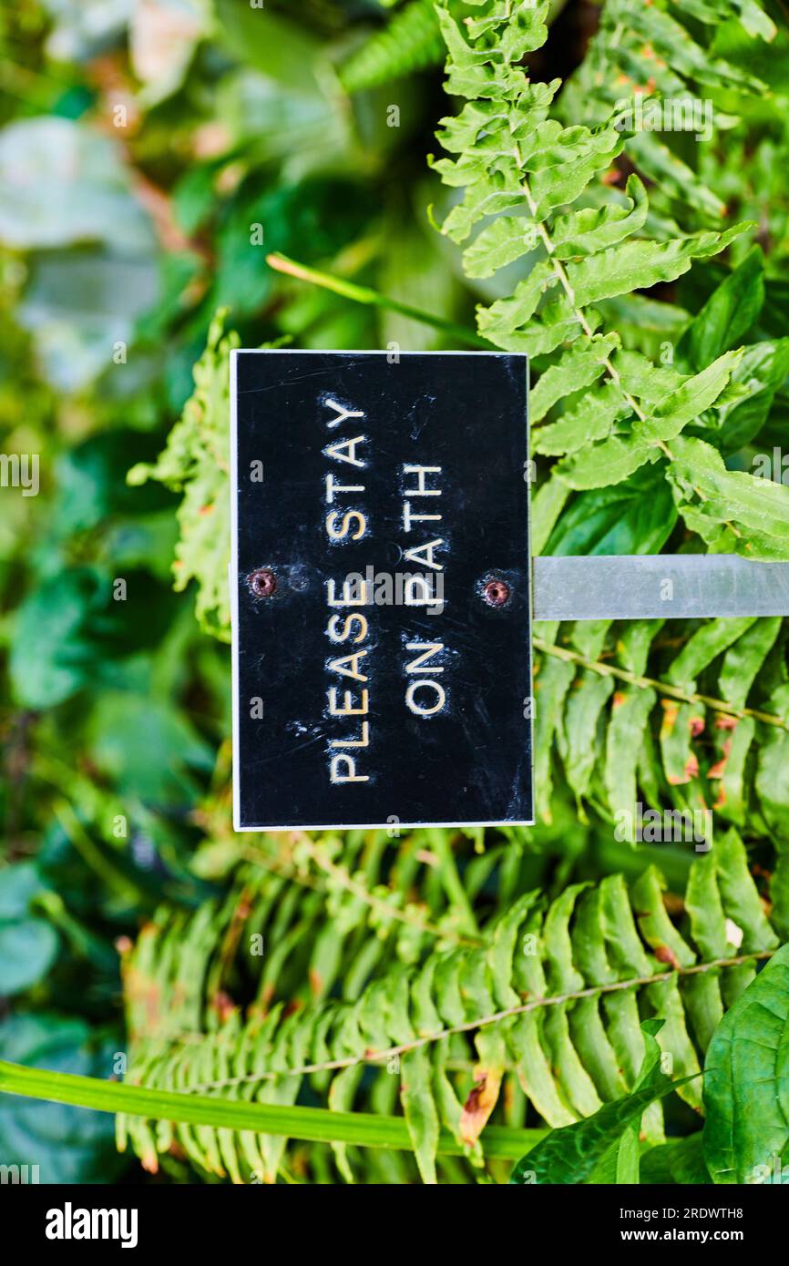 Please Stay On Path black sign with white letters in front of tropical ...