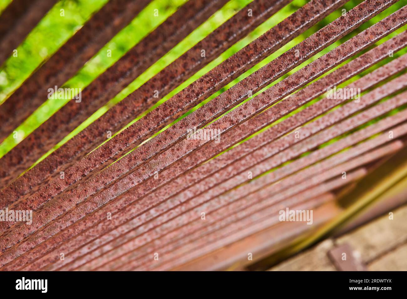 Macro red and dark brown metal spokes or square bars over blurry tree ...