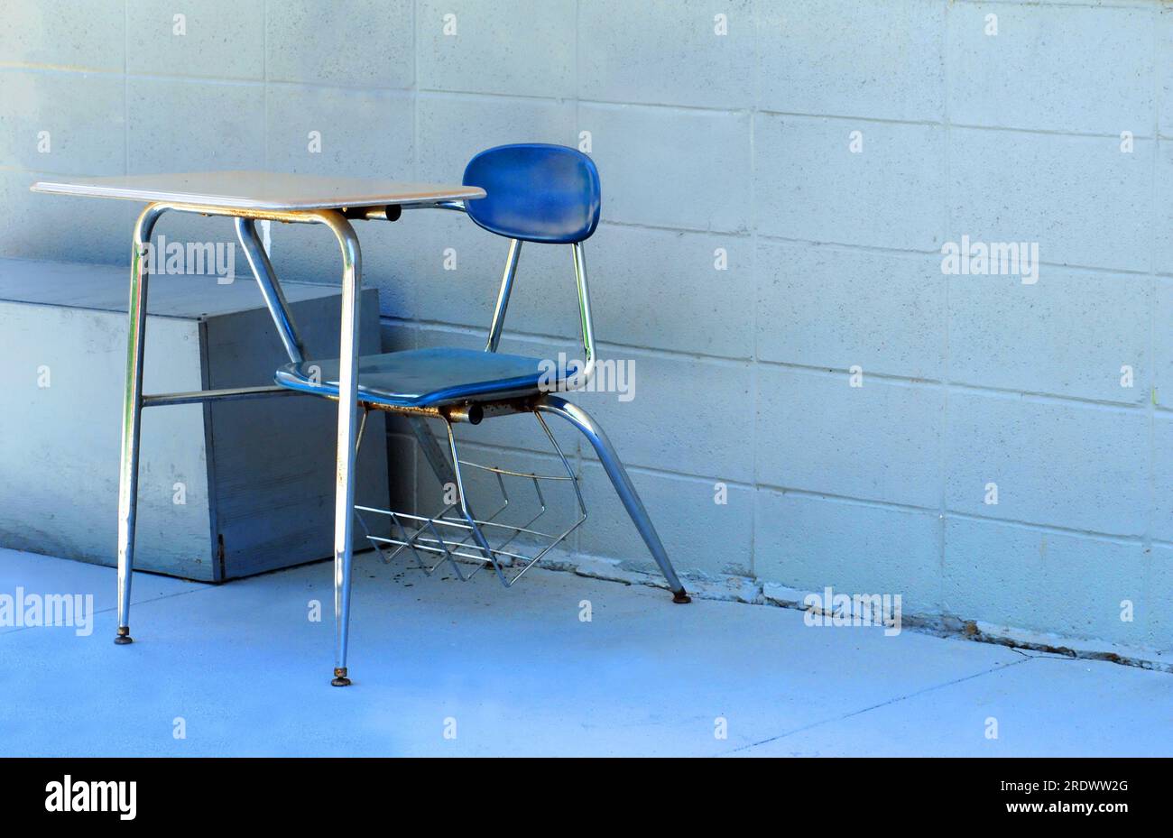 Rusting metal school desk sits in alley behind school. It has been ...