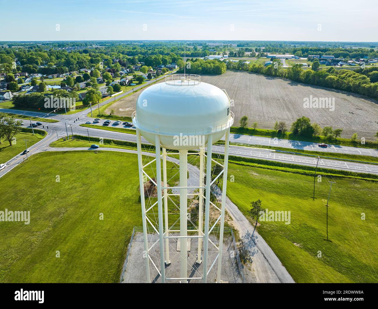 Aerial of backside of a white water tower on cement slab in summer ...