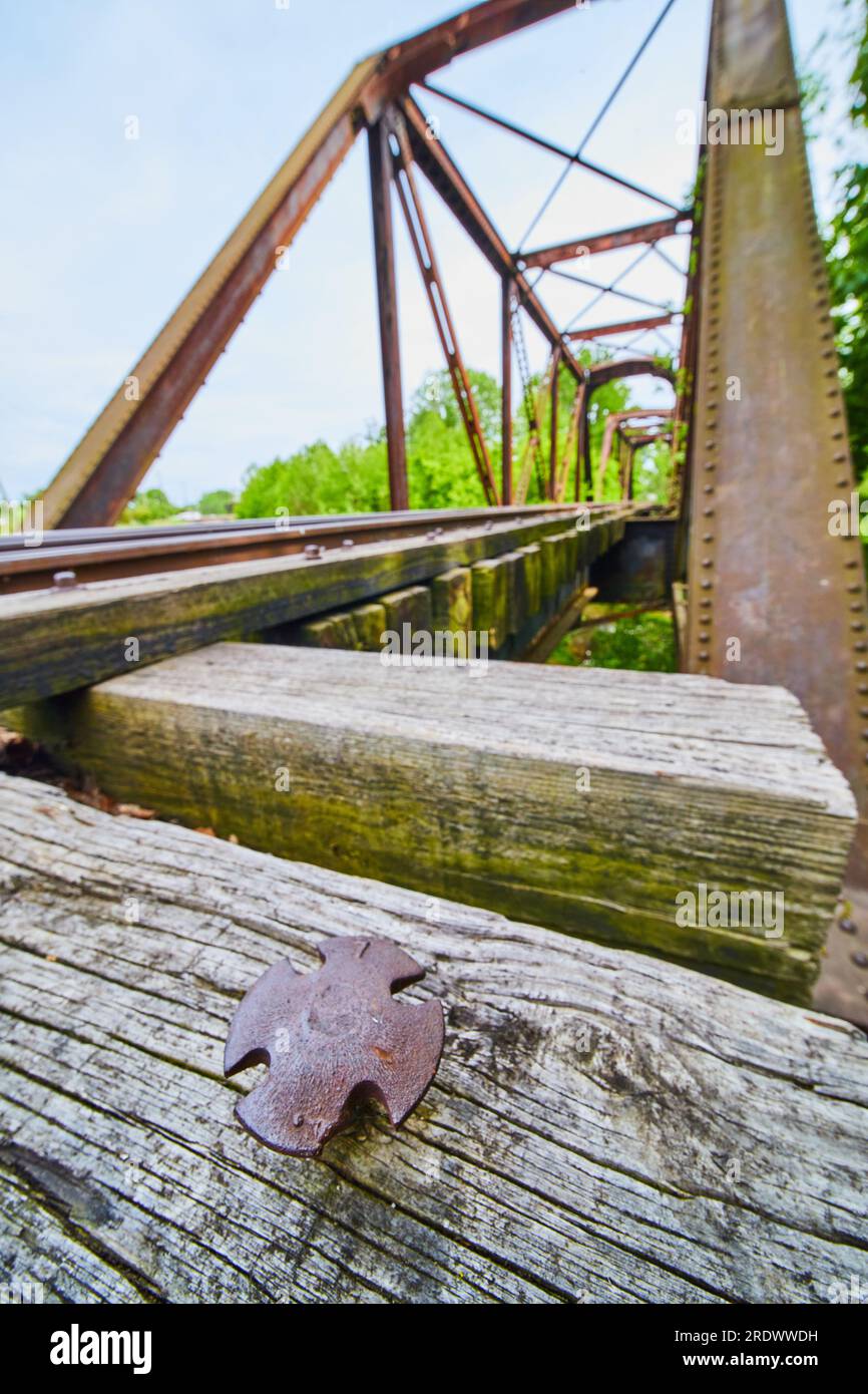 Cross shaped nail head on textured wood of distant blurred railroad ...