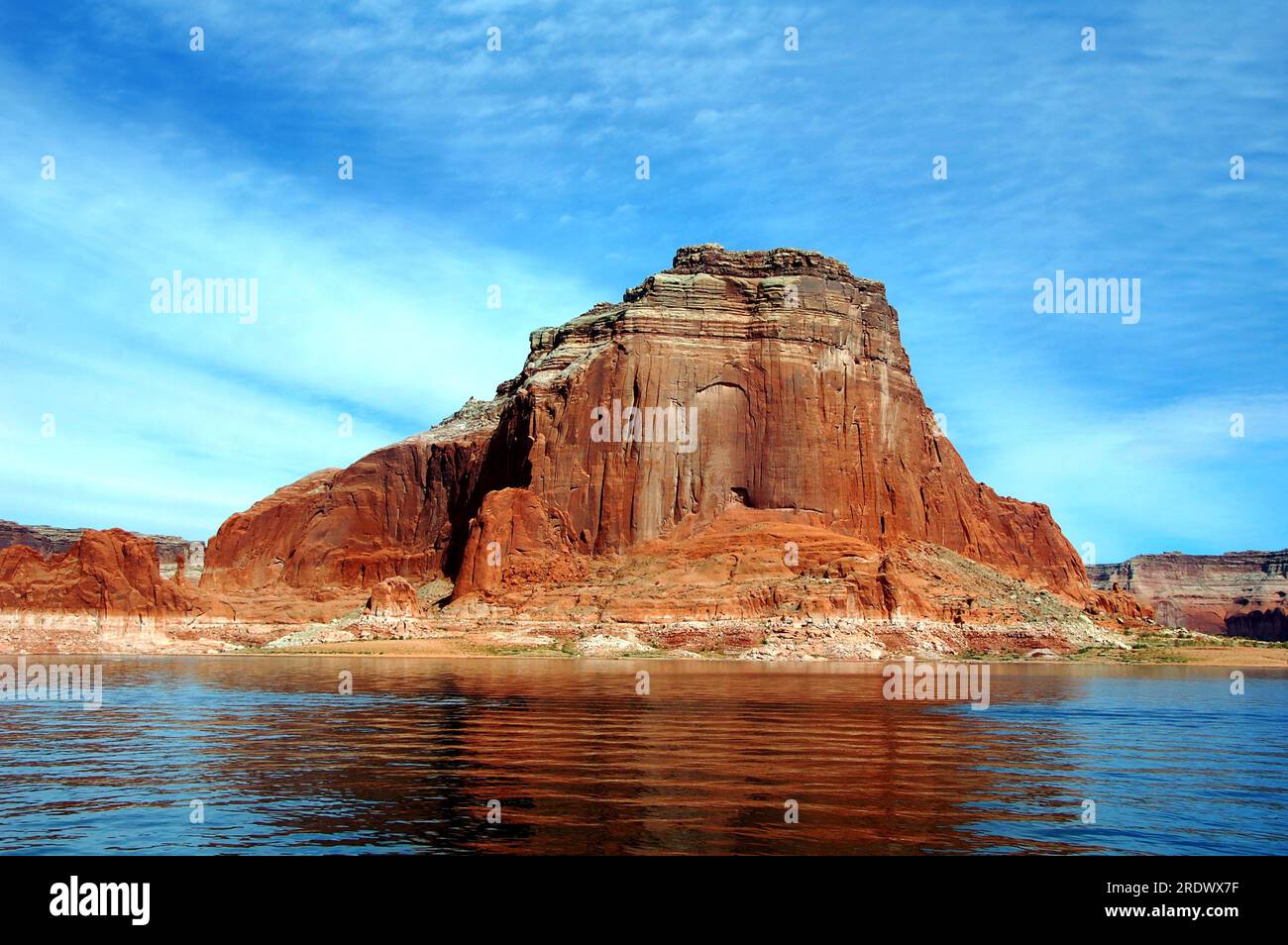Red sandstone monolith is reflected in the blue waters of Lake Powell ...