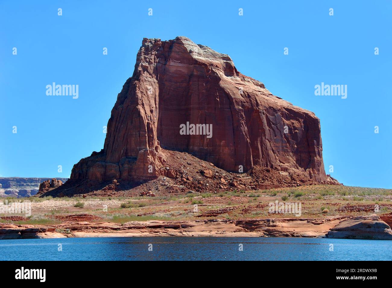 Red sandstone formation rises from the arid shoreline of Lake Powell ...