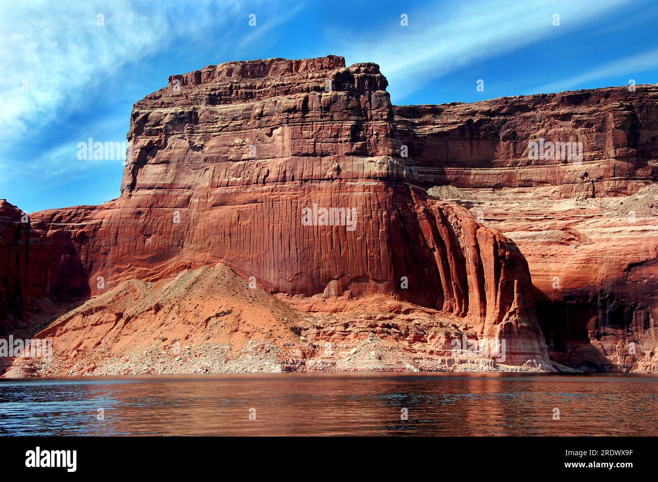 Red sandstone cliff reaches for blue sky along the shores of Lake ...