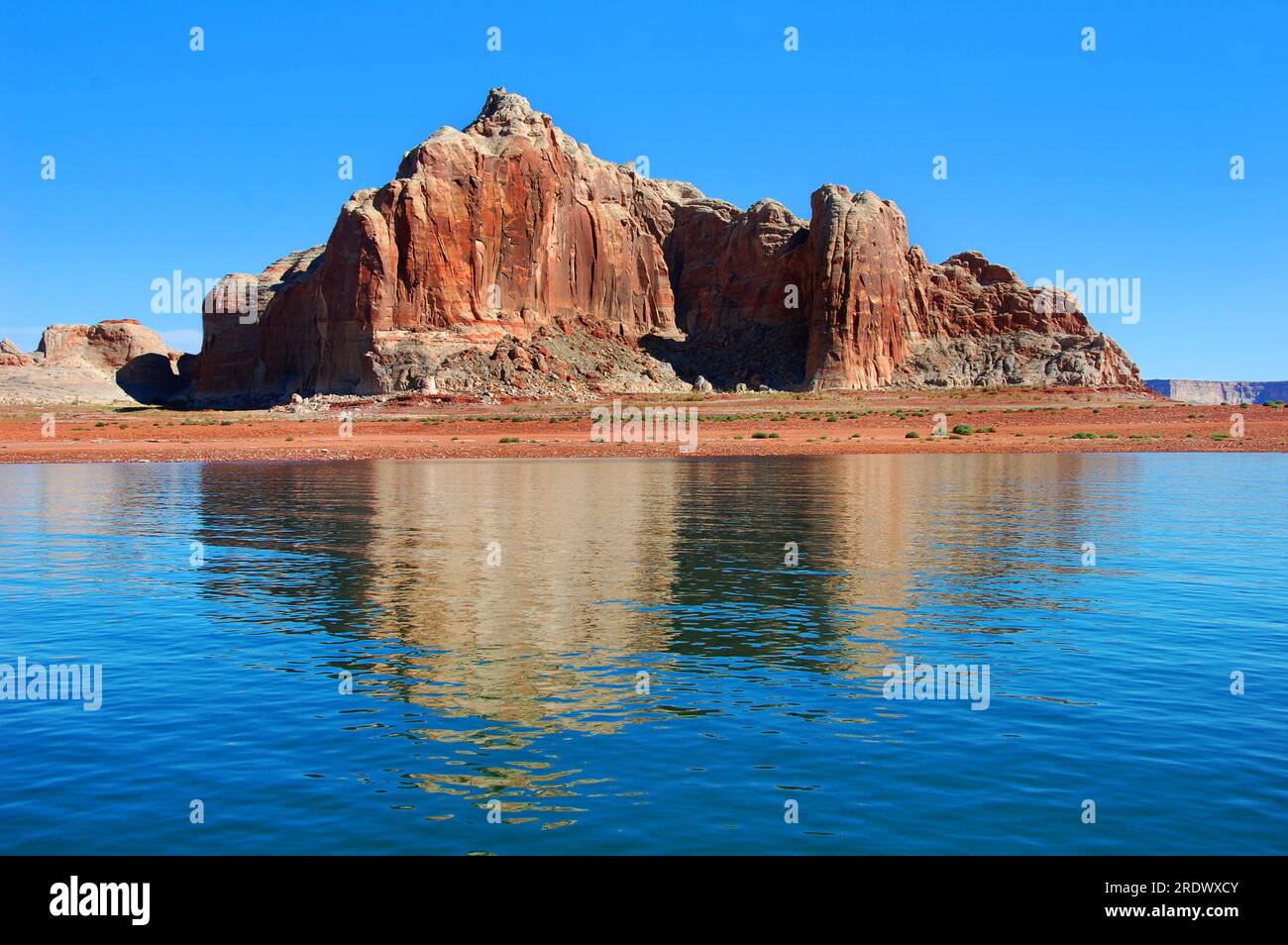 Sandstone monolith is reflected in the calm waters of Lake Powell in ...