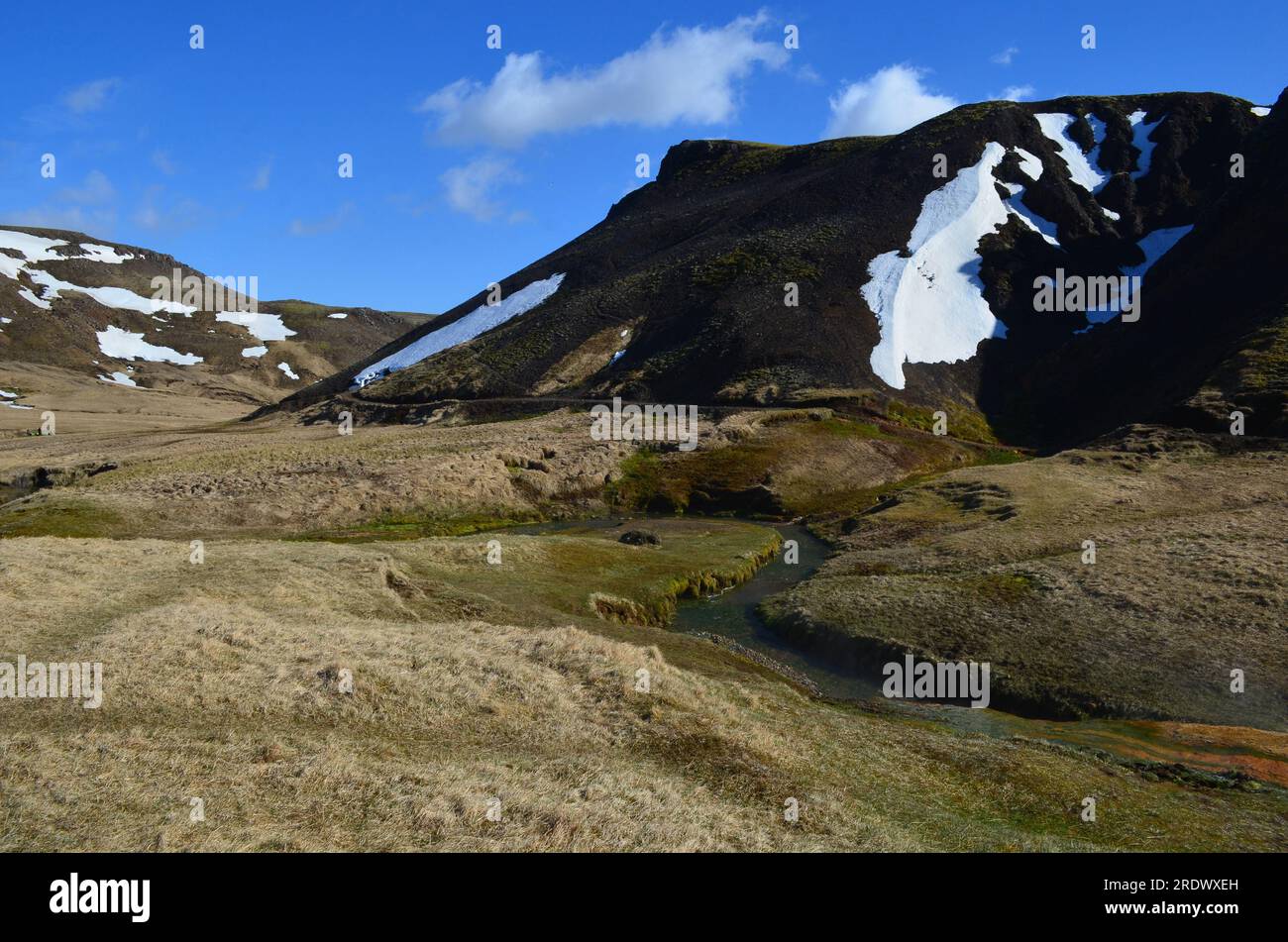 Landscape with a hot spring river and snow on surrounding mountain ...