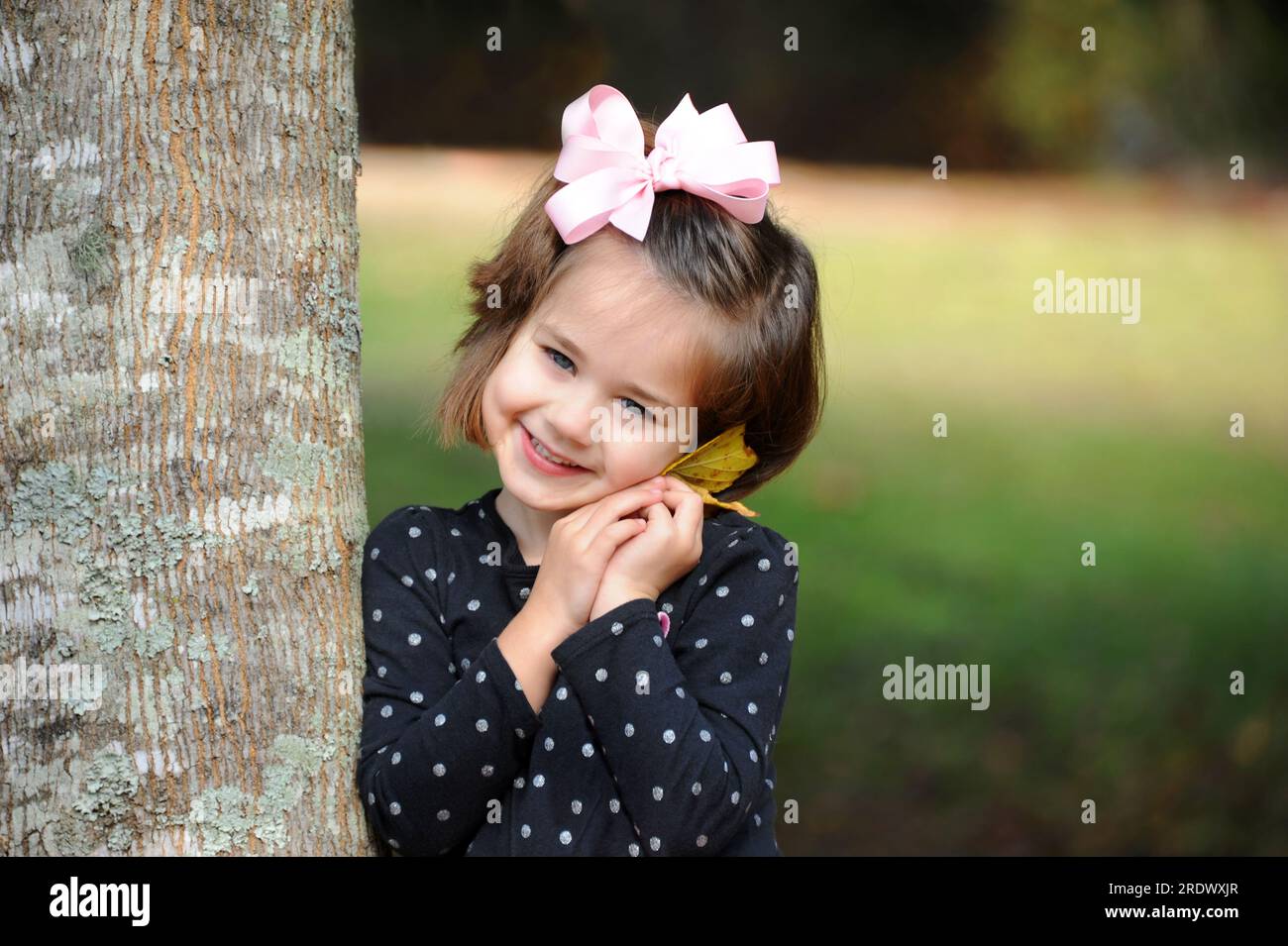 Little girl hugs a single yellow leaf and smiles with joy. She is ...