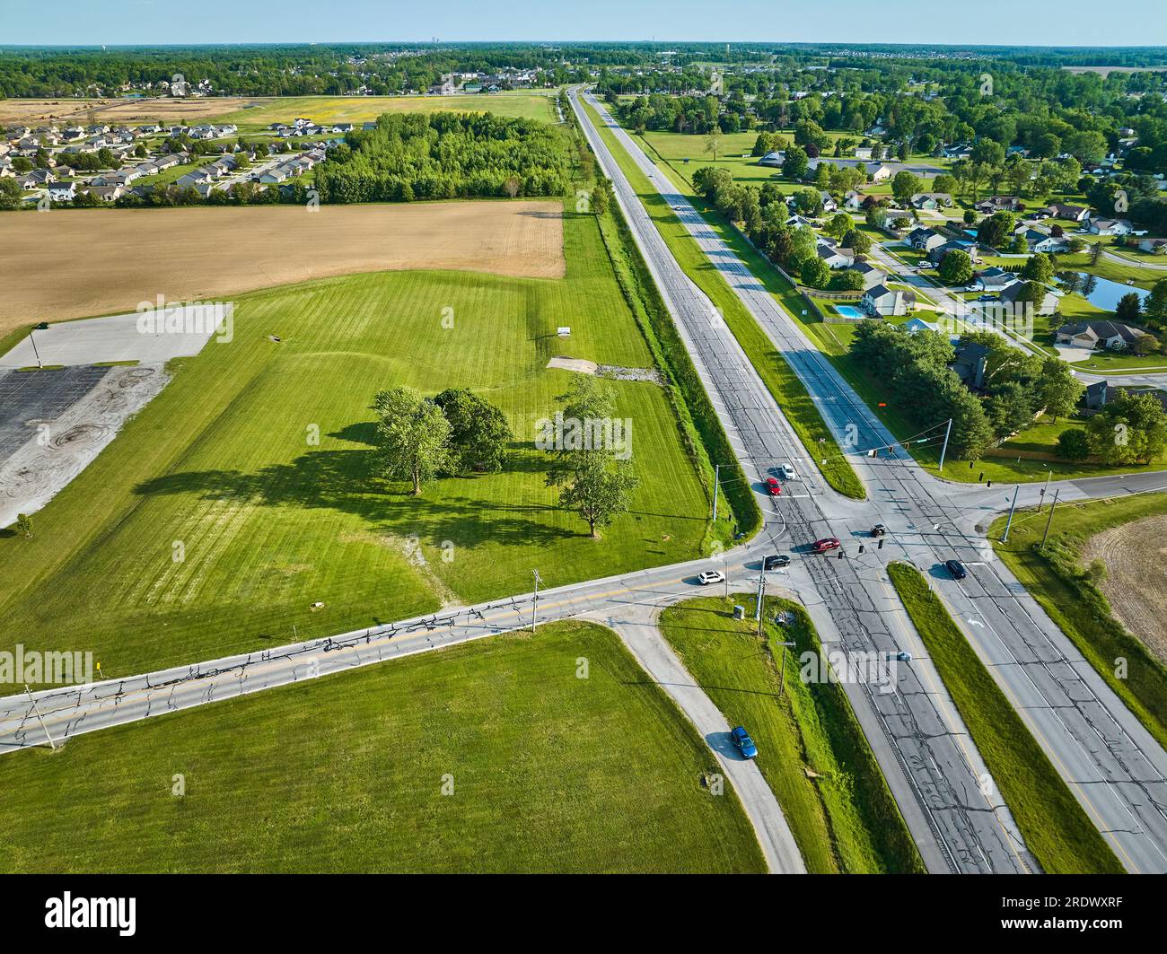 H road intersection aerial with distant houses and trees in a field ...