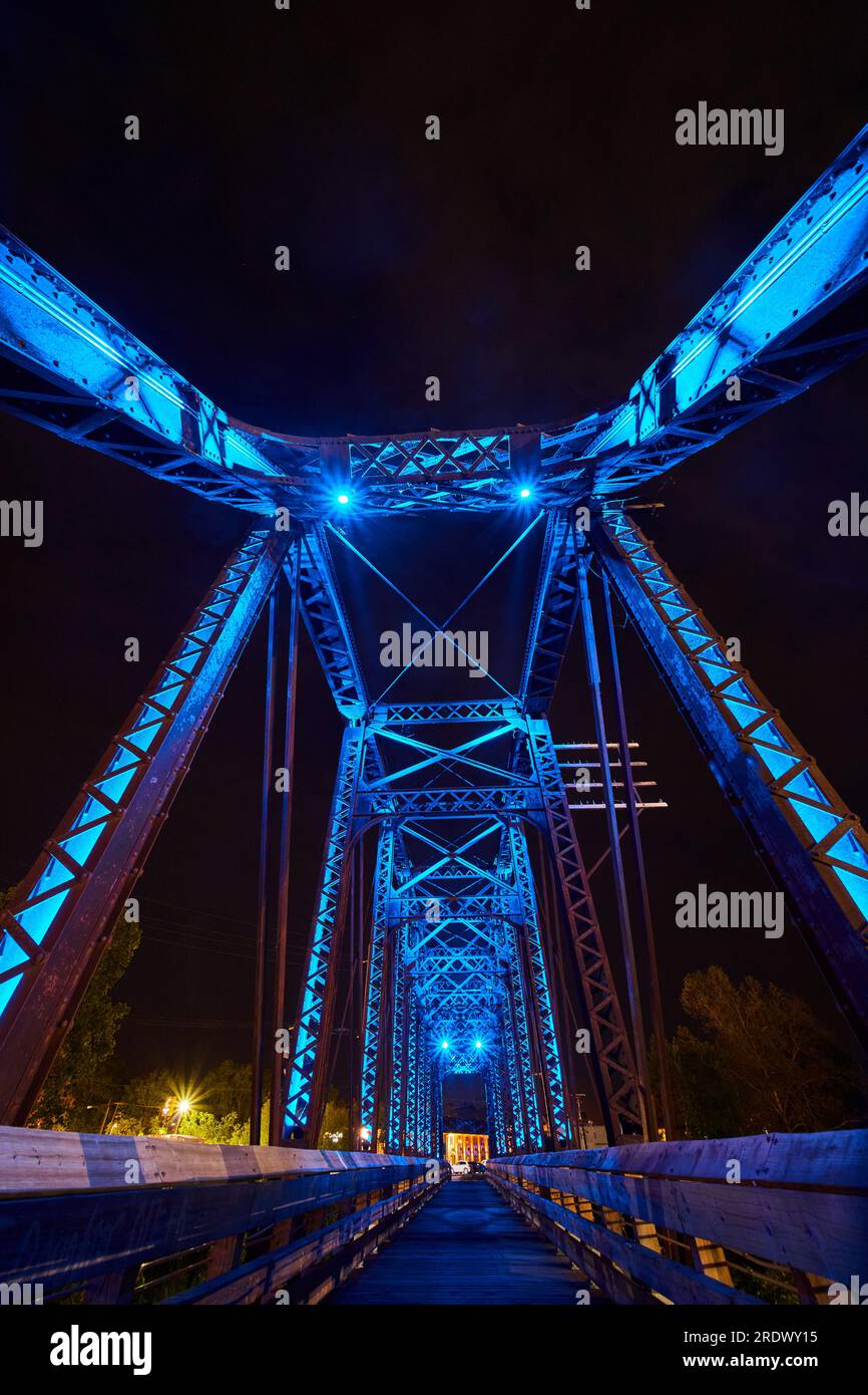 Black sky above glowing neon blue truss railroad bridge with wooden ...