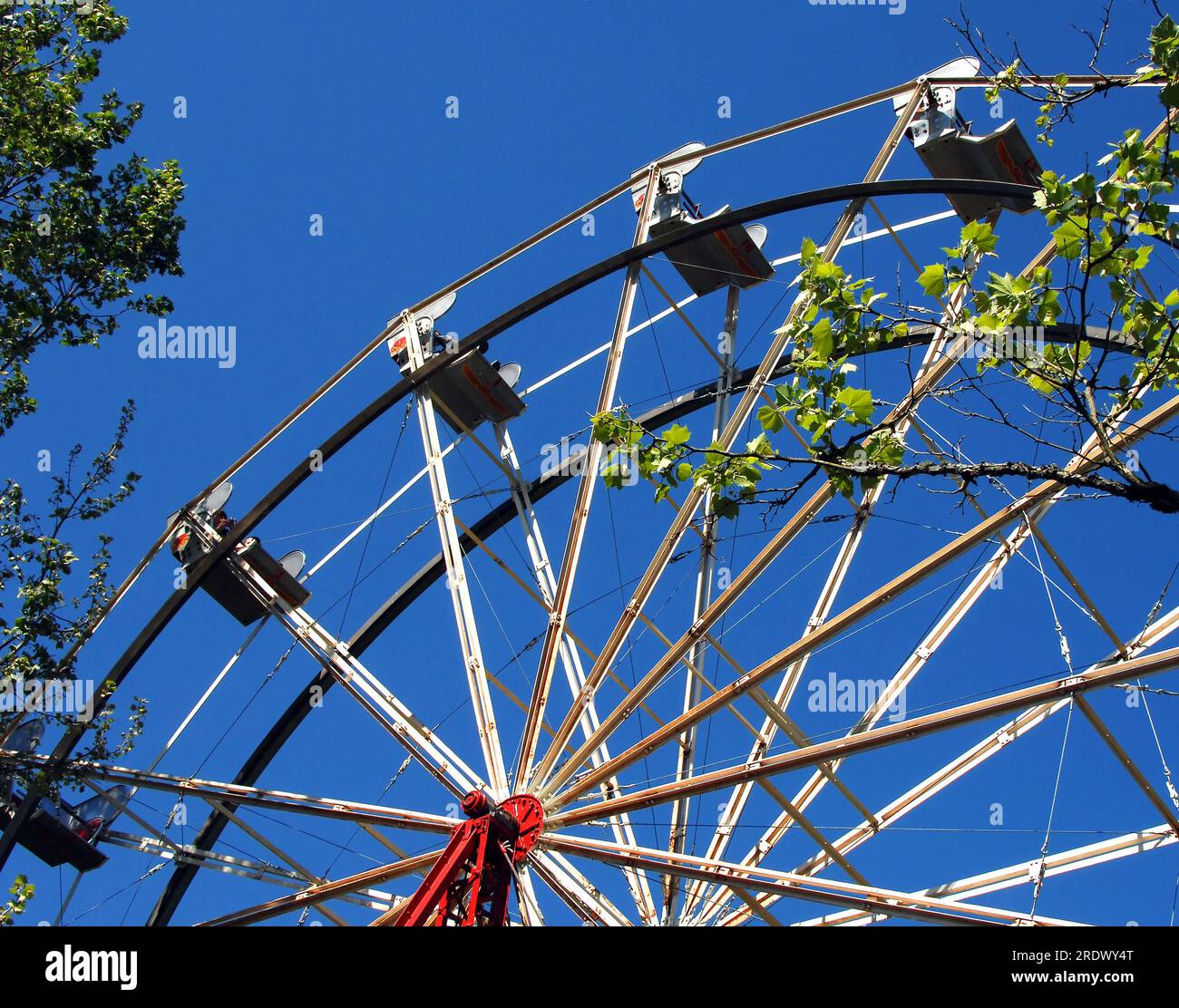 Ferris Wheel circles up into a vivid blue sky. Cars are empty Stock ...