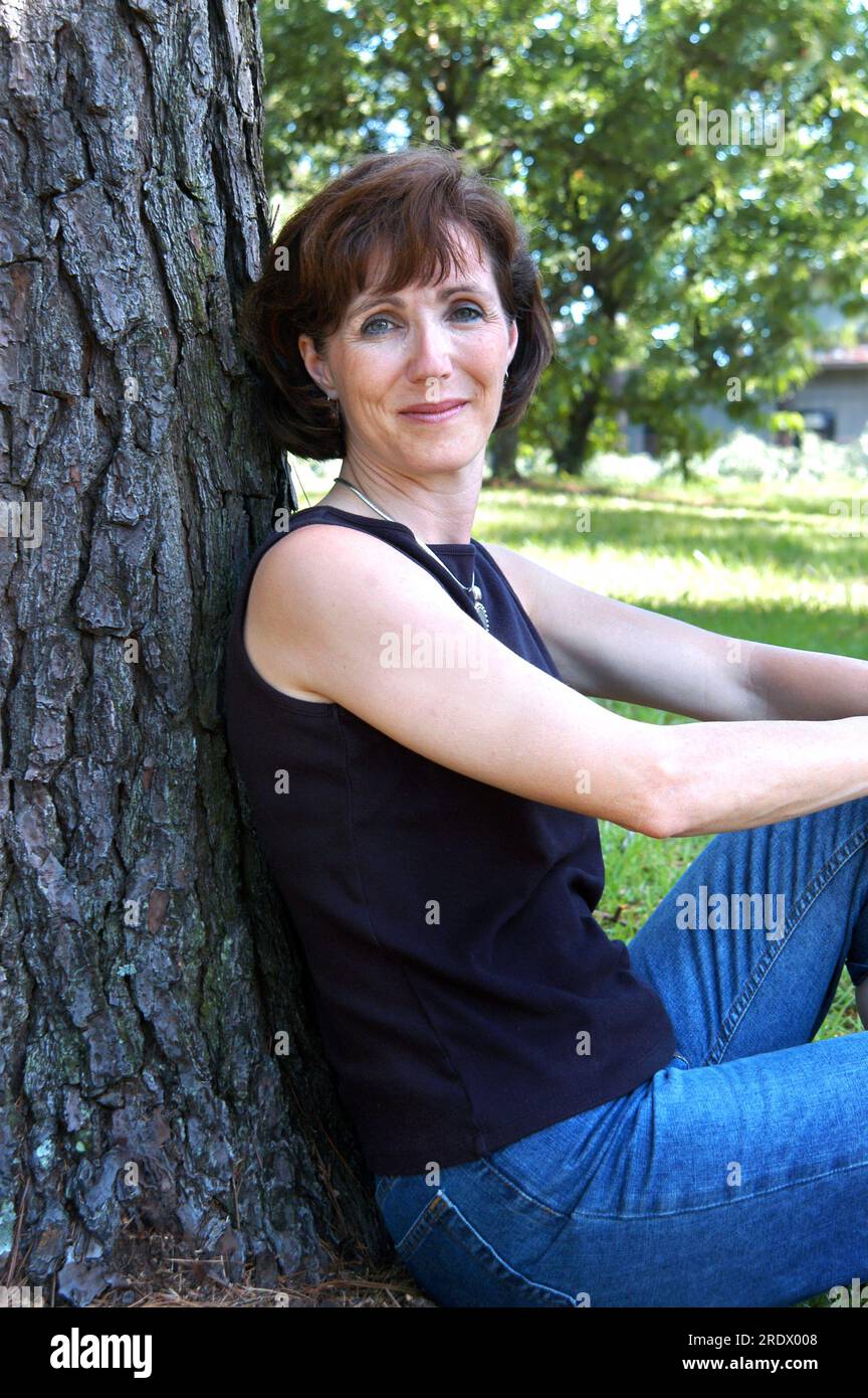 Woman sitting against tree trunk hi-res stock photography and images ...
