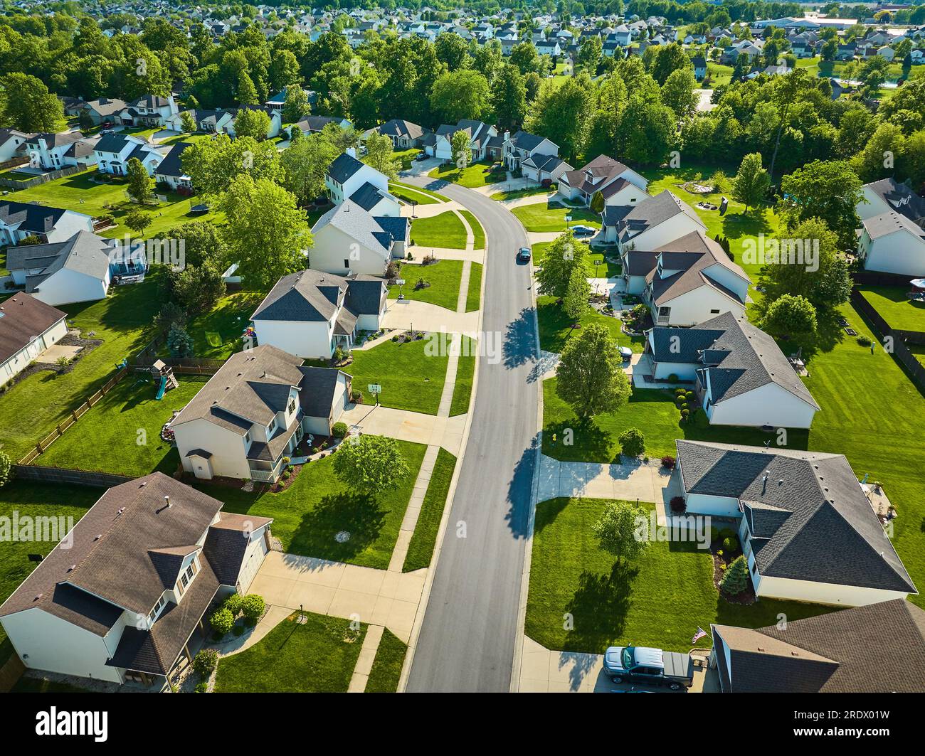 Aerial over street in neighborhood with tall houses and distant ...