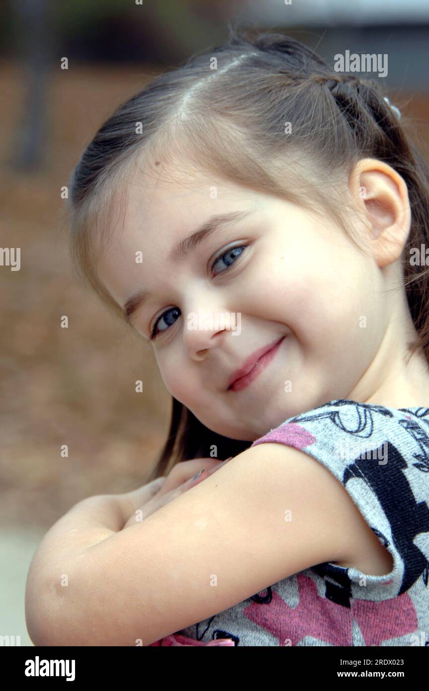 Little girl crosses her arms and gives a smug smirk. She has brown hair ...