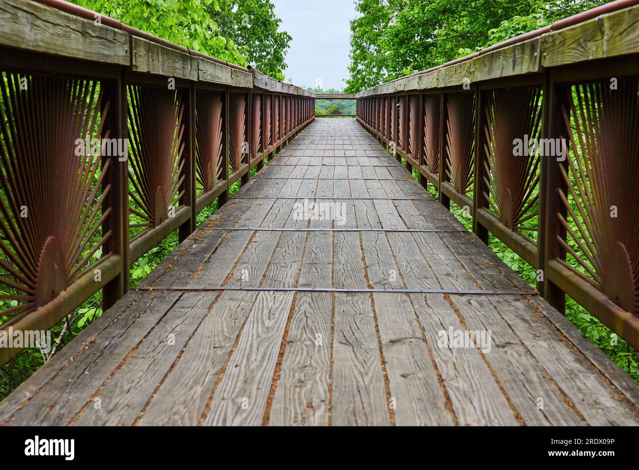 Low angle of bridge with setting sun pattern on railing and wooden ...