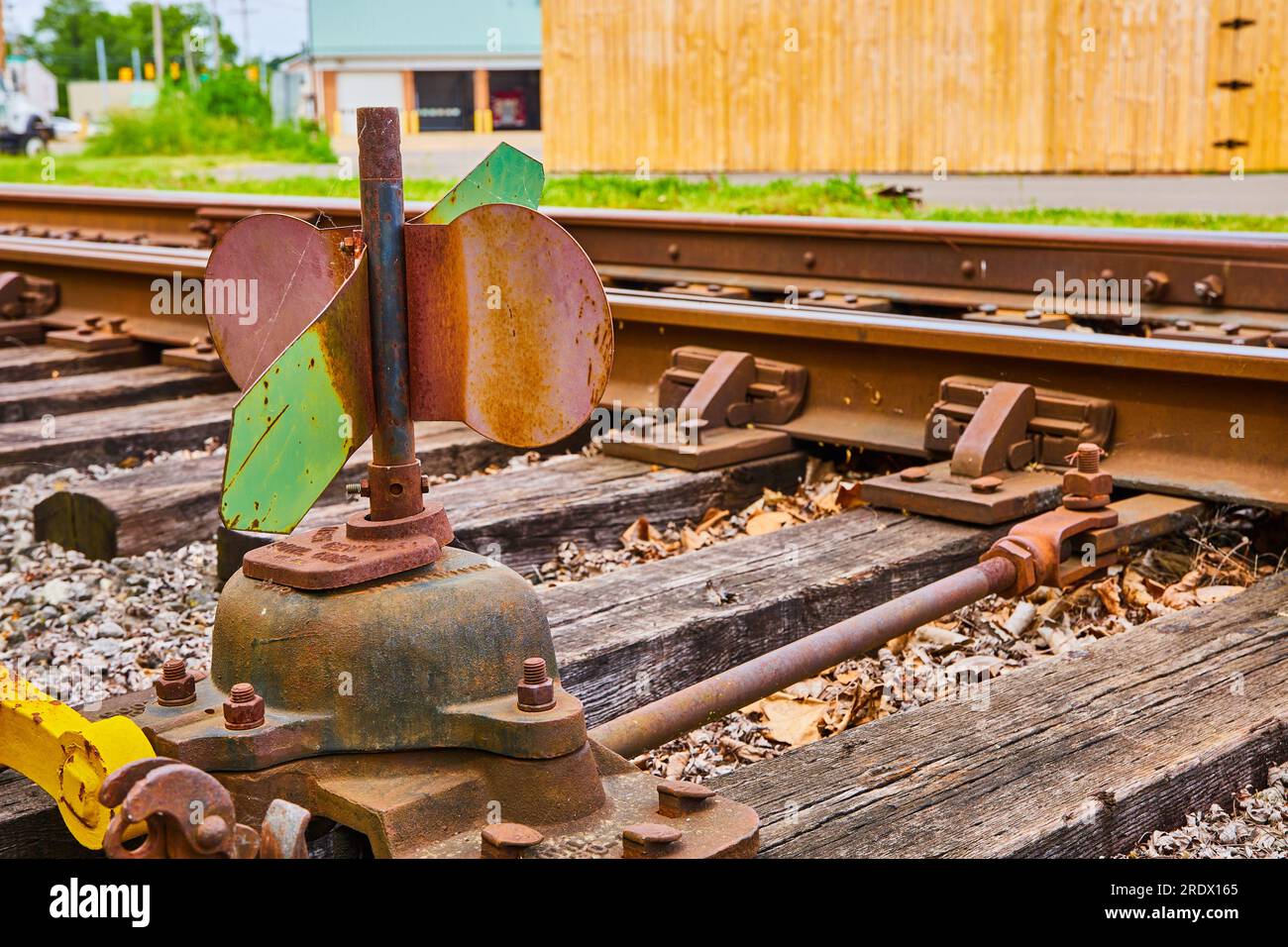 Rusty railroad switch with green paint and yellow lever next to train ...
