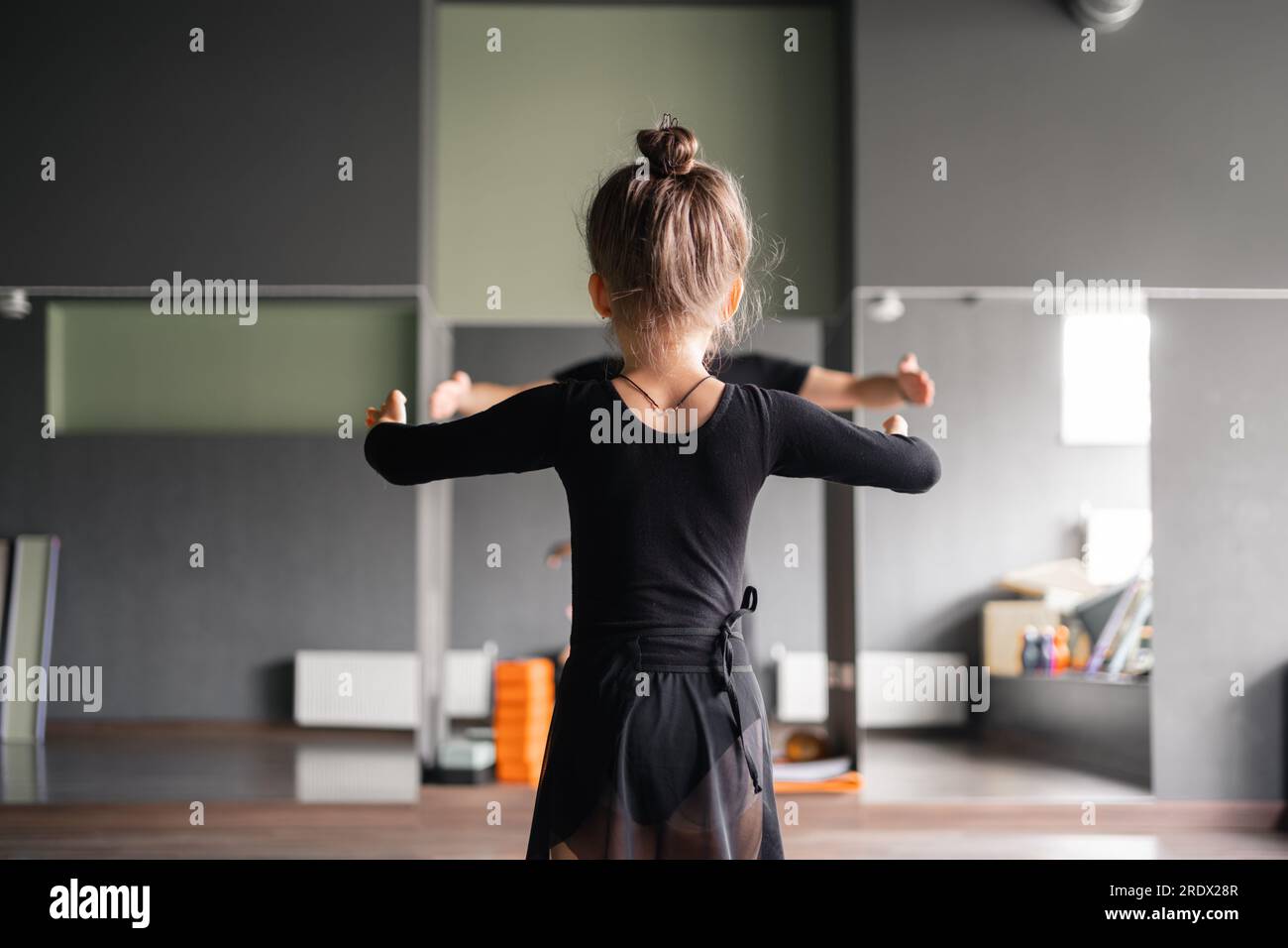 Child girl standing in black sport bodysuit in dancing studio during ...