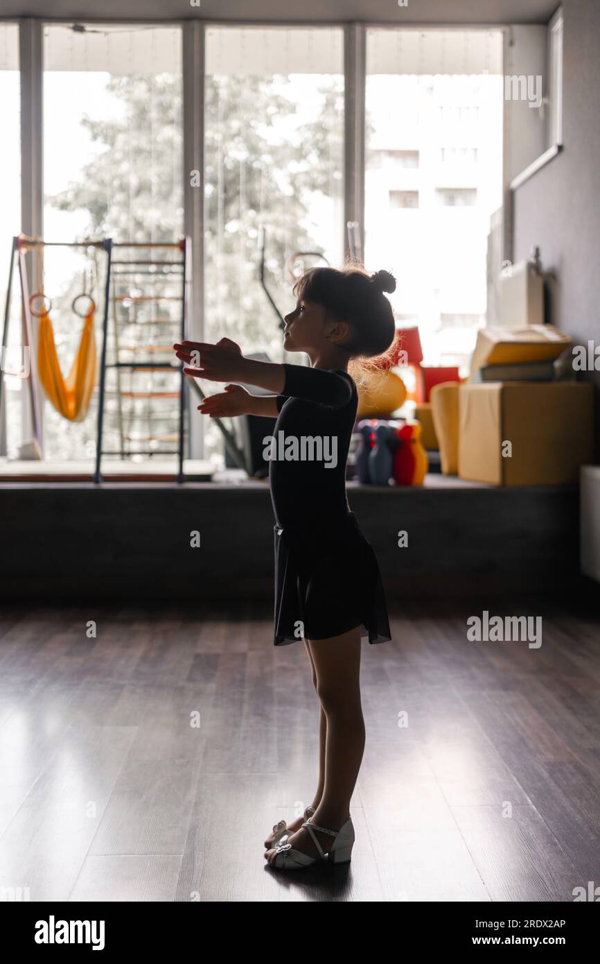 Child girl standing in black sport bodysuit in dancing studio during ...
