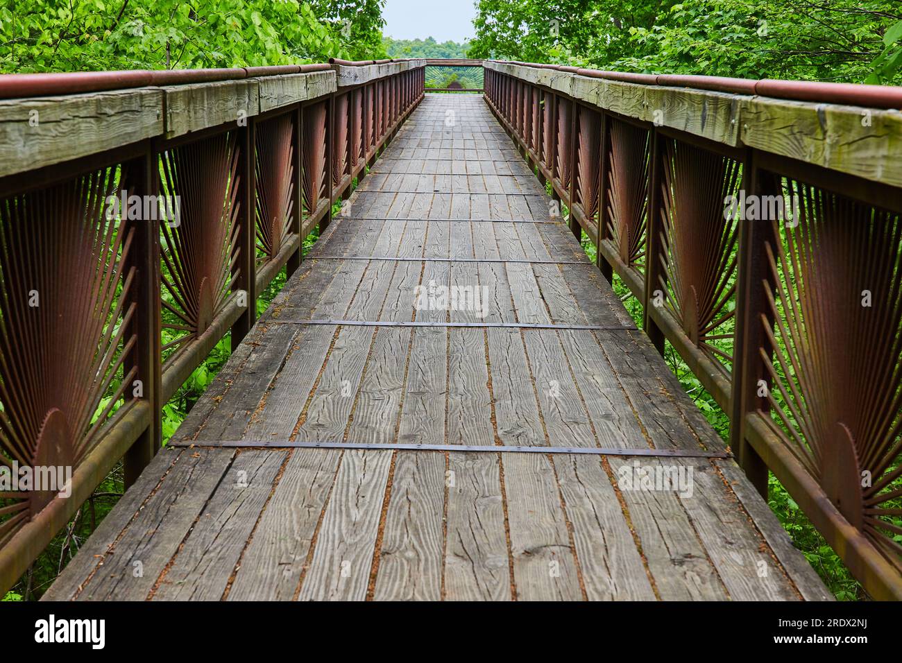 Long view of bridge with worn planks and rusty rising sun pattern on ...