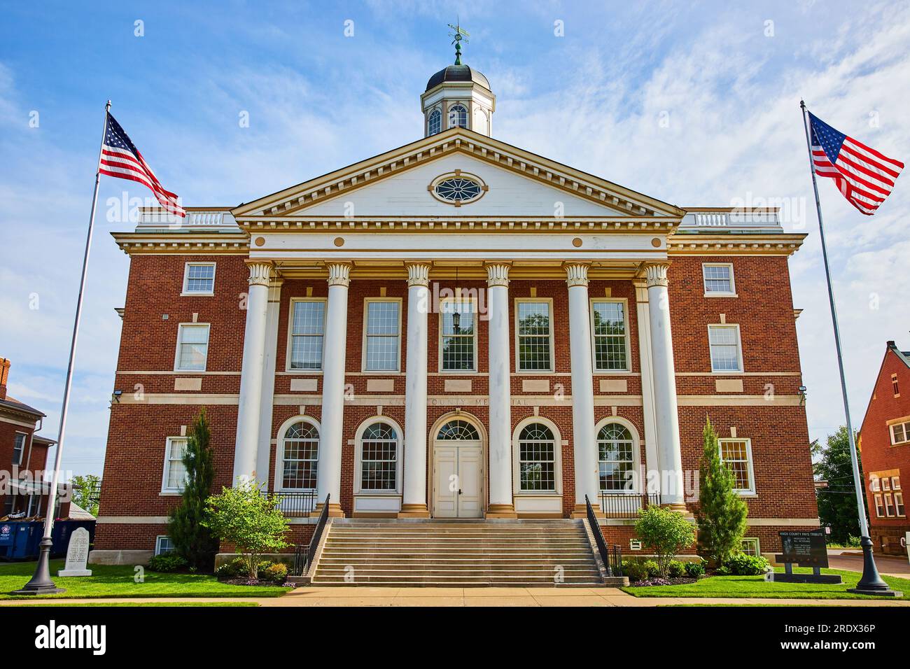 Exterior of red brick building that has white pillars with blue sky and ...
