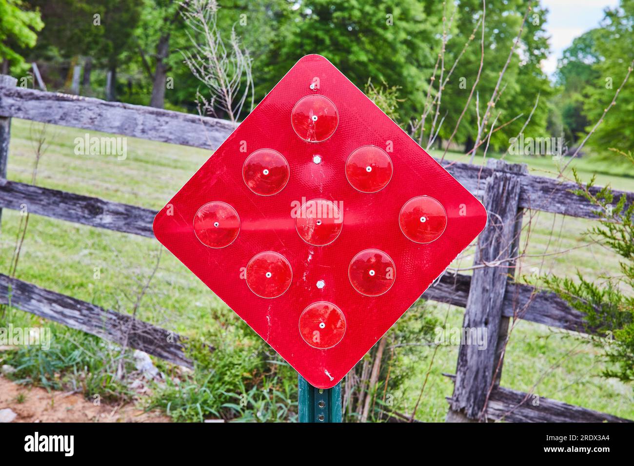Red caution street sign with nine reflector circles in front of ...