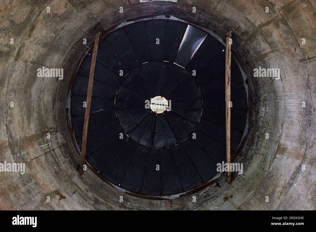 Interior of concrete silo with black camera shutter like roof or ...