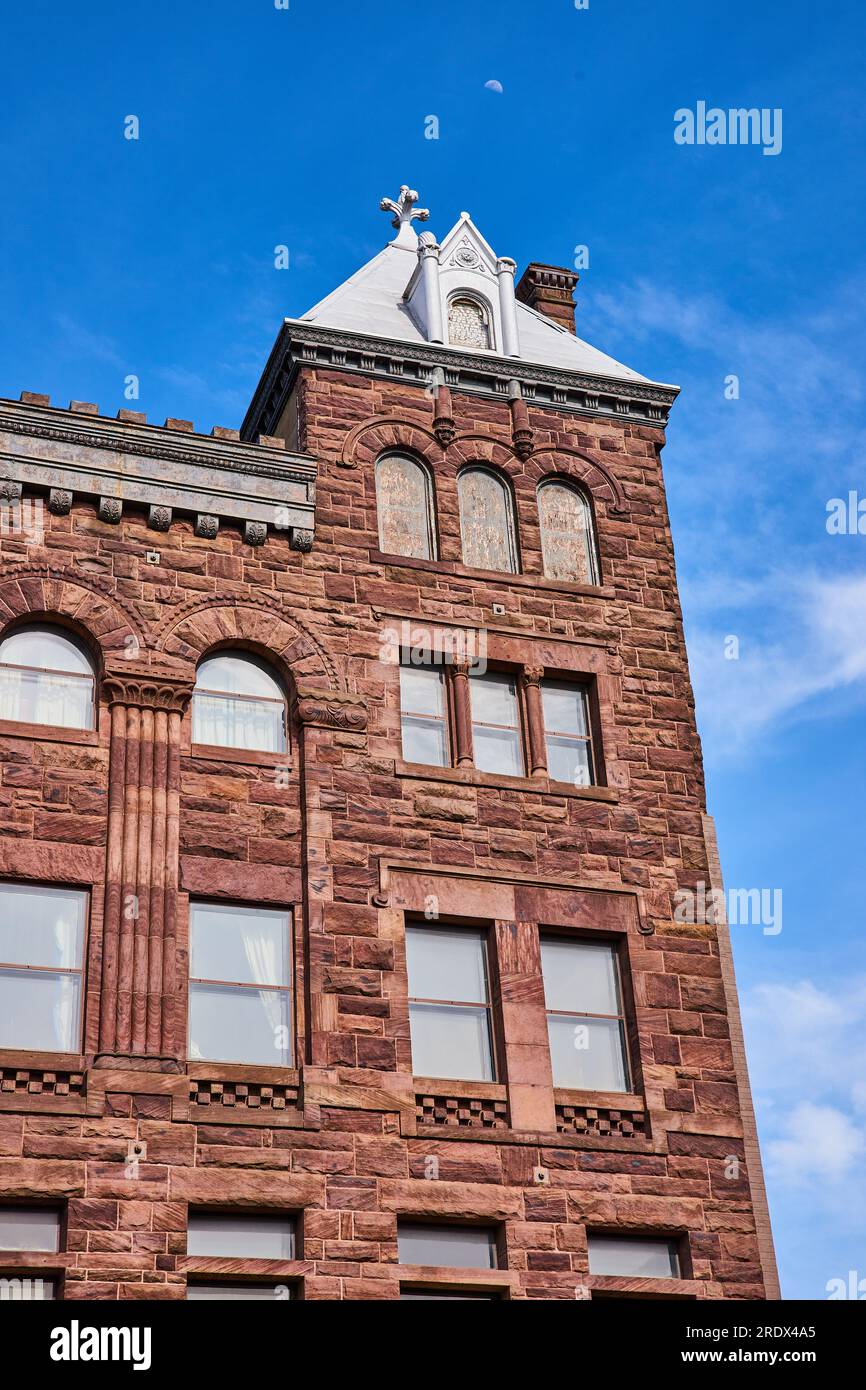 Vertical of old dark brown brick building with fancy roof and half moon ...