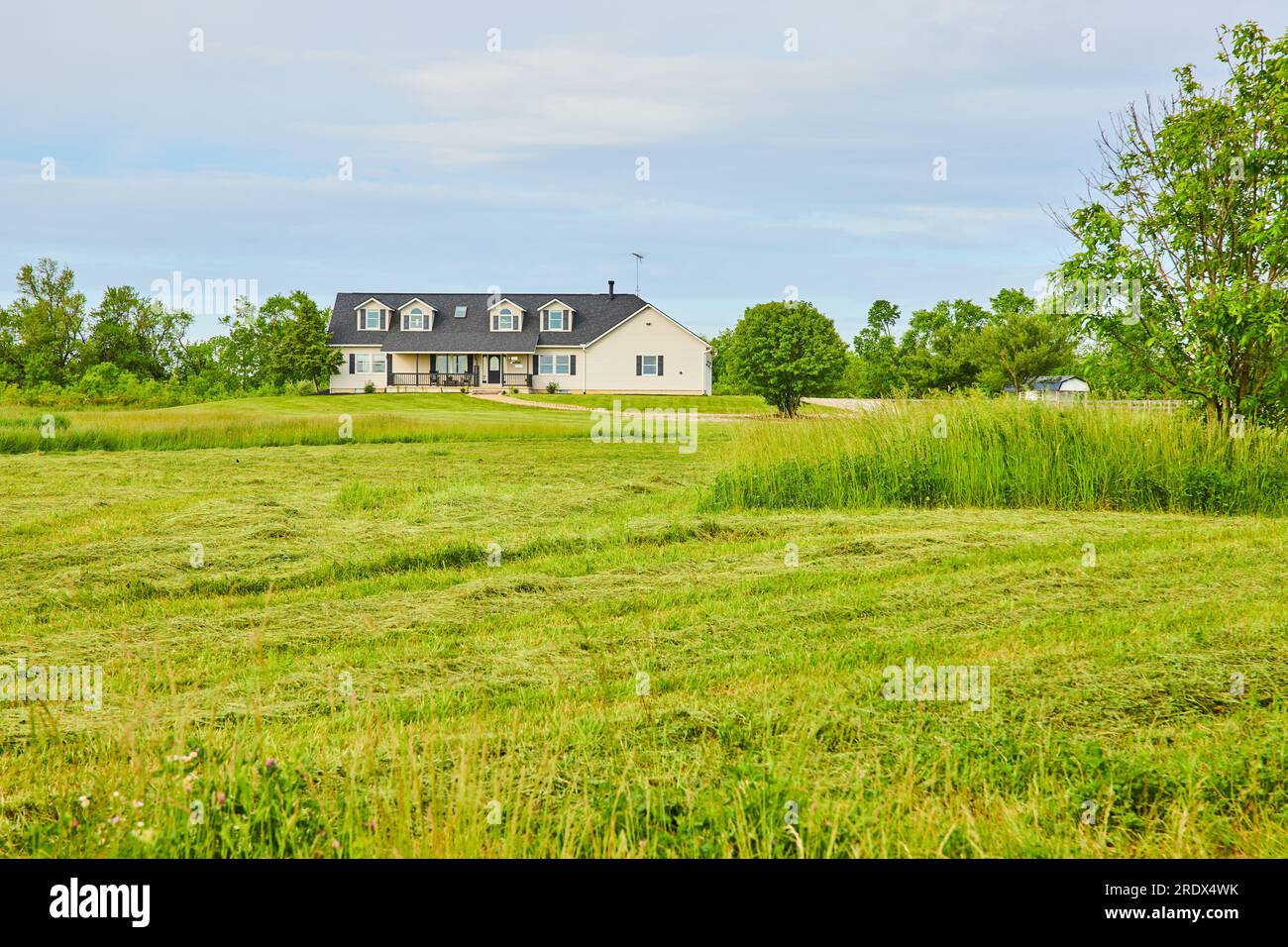Pretty blue and purple sky with distant country house with fields of ...