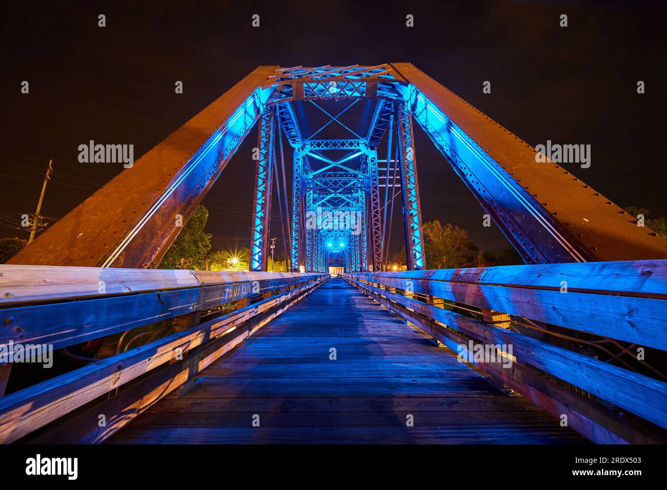 Bright neon blue lights on wooden walking bridge inside truss railroad ...