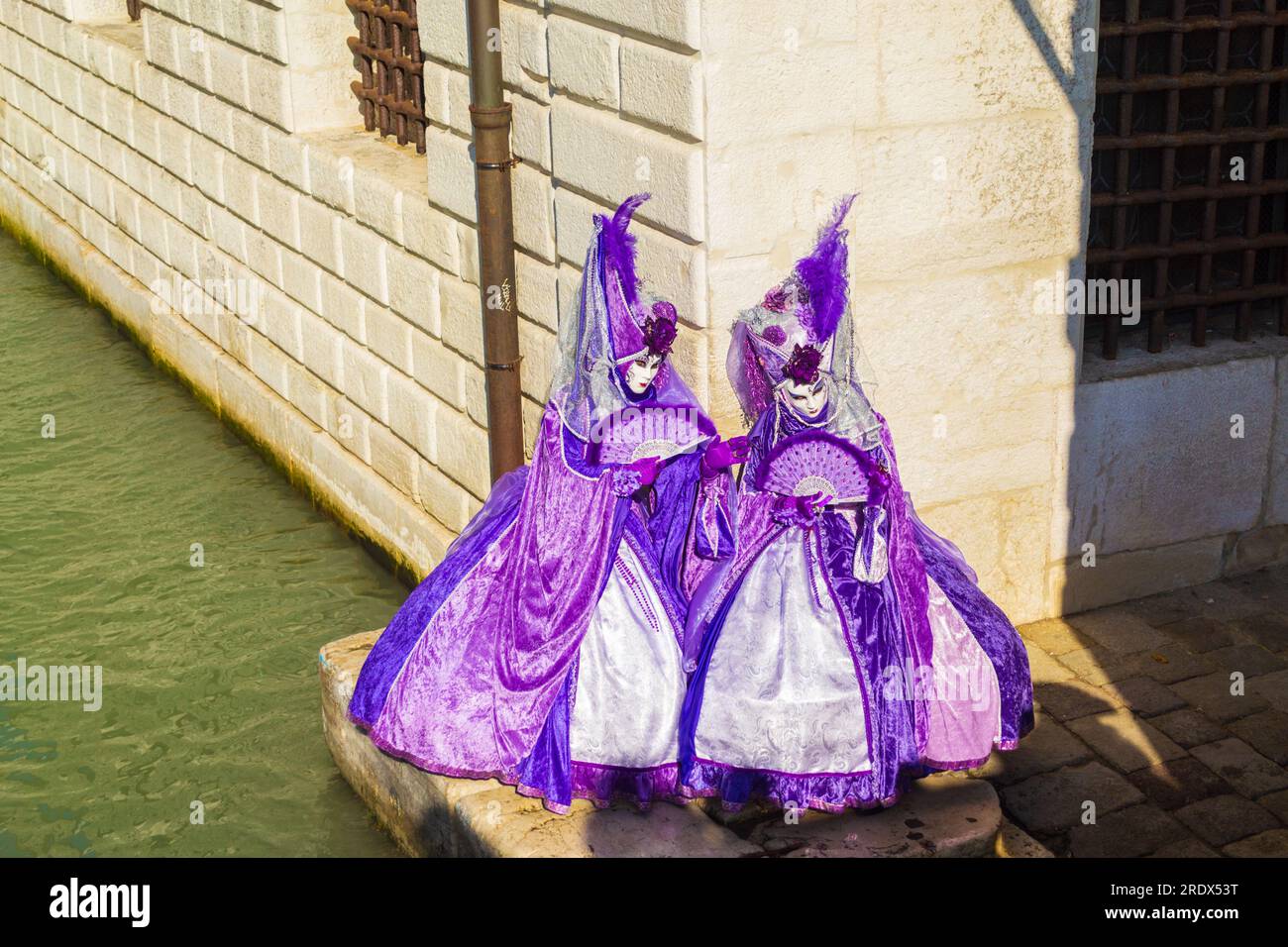 Disguised women dressed in spectacular bright purple costumes posing by ...