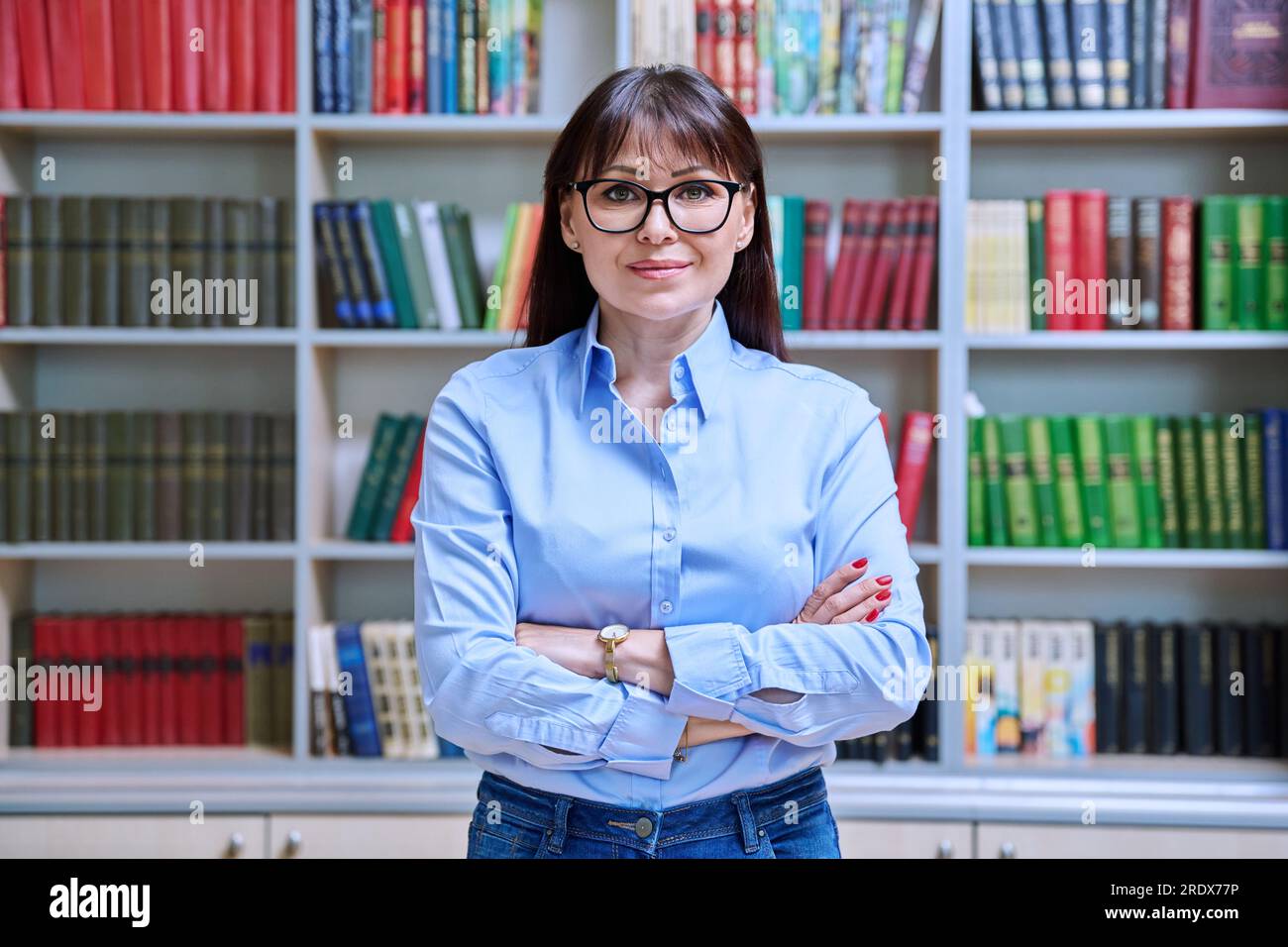 Portrait of confident female teacher with crossed arms inside library Stock Photo - Alamy