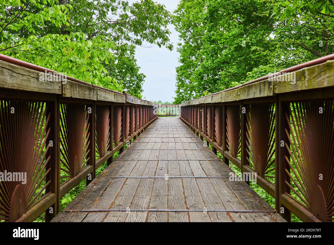 Bridge with rusty rising sun pattern on railing with worn wooden plank ...
