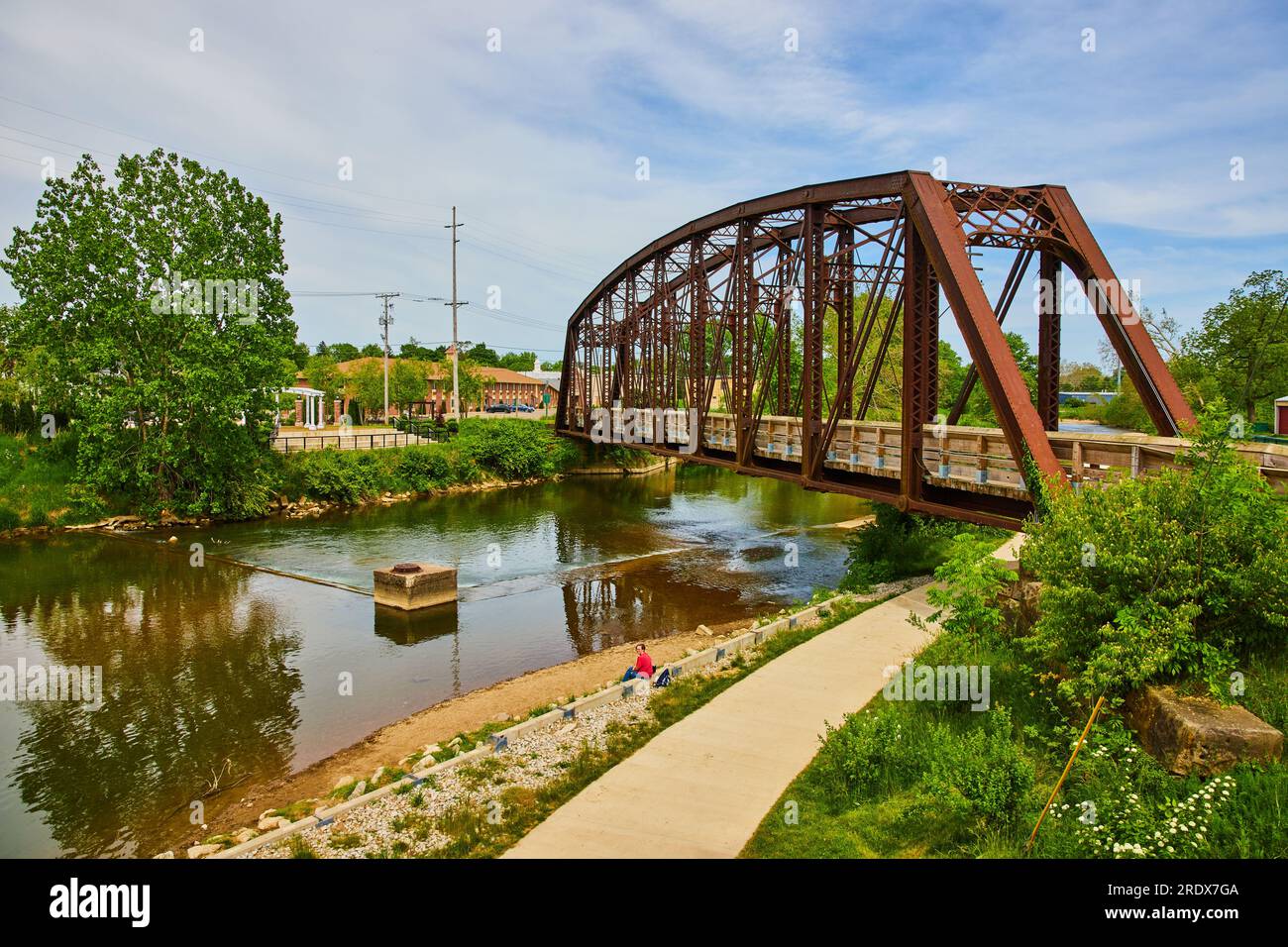 Person sitting on concrete wall under iron bridge with flowing river in ...