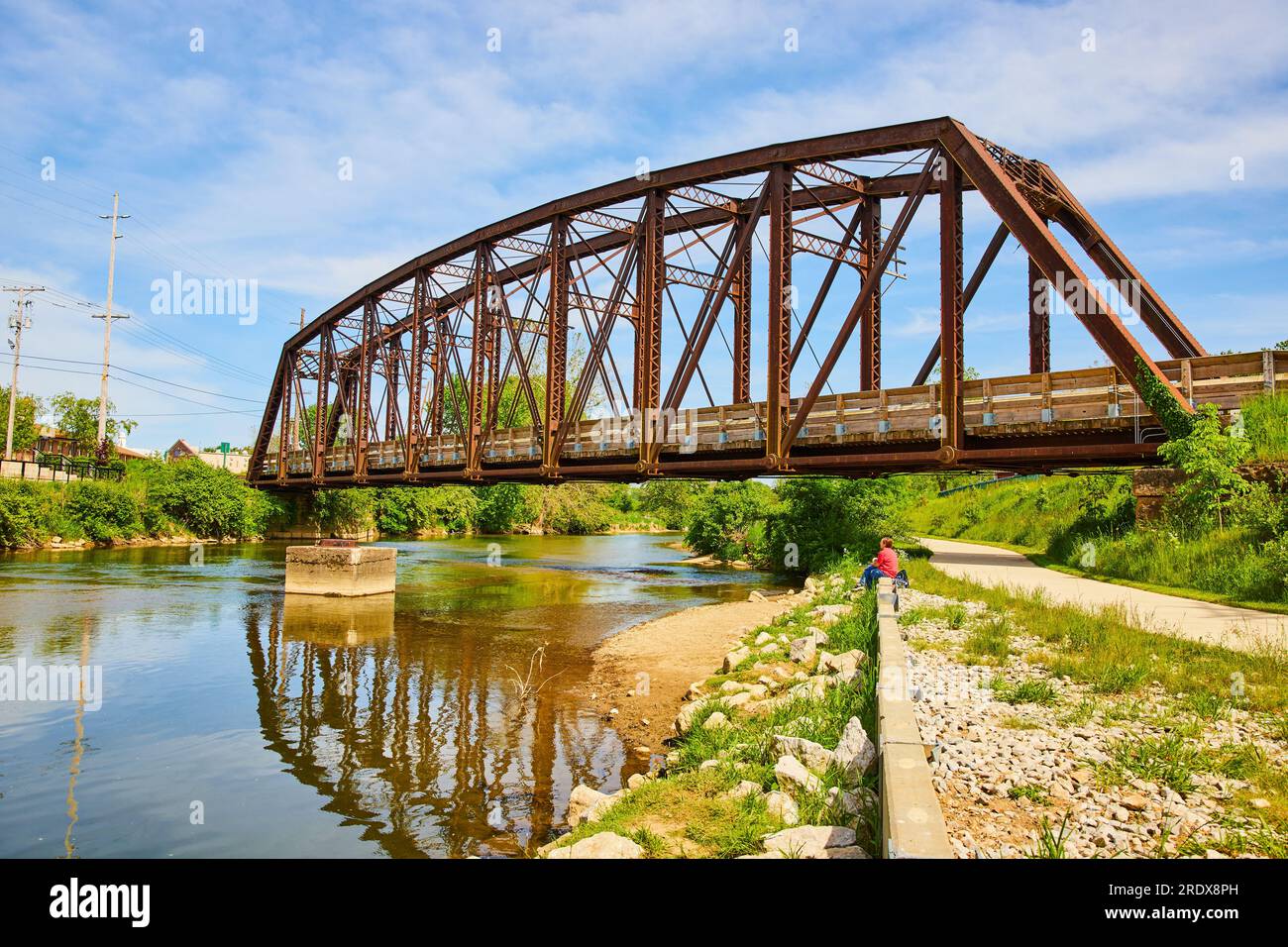 Person sitting on concrete wall with old train bridge converted into ...