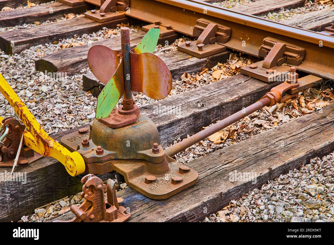 Rusty railroad switch with green paint and yellow lever on train tracks ...