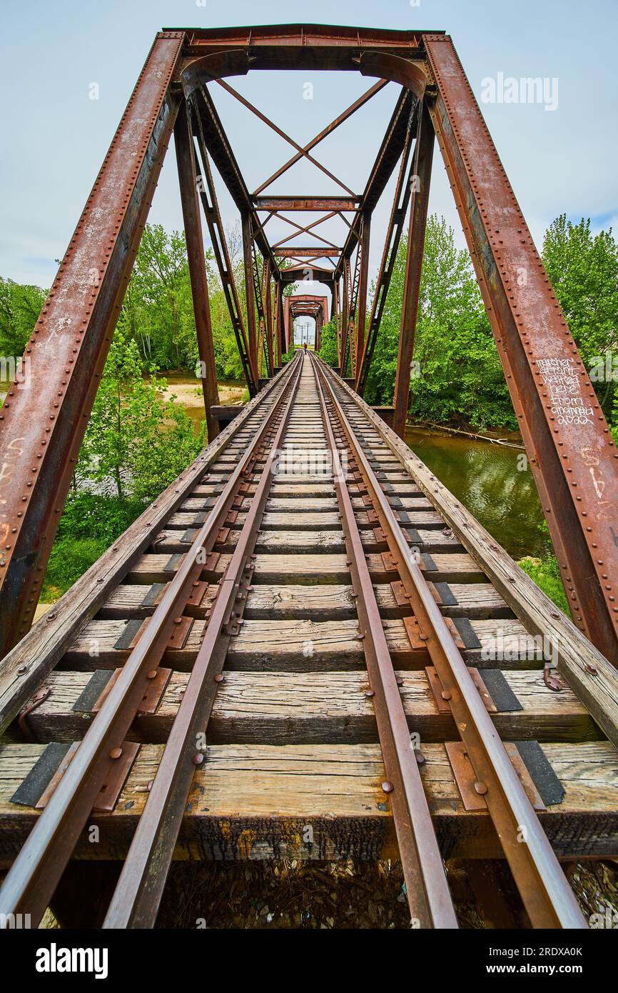 Distant person walking along train tracks on iron truss railroad bridge ...