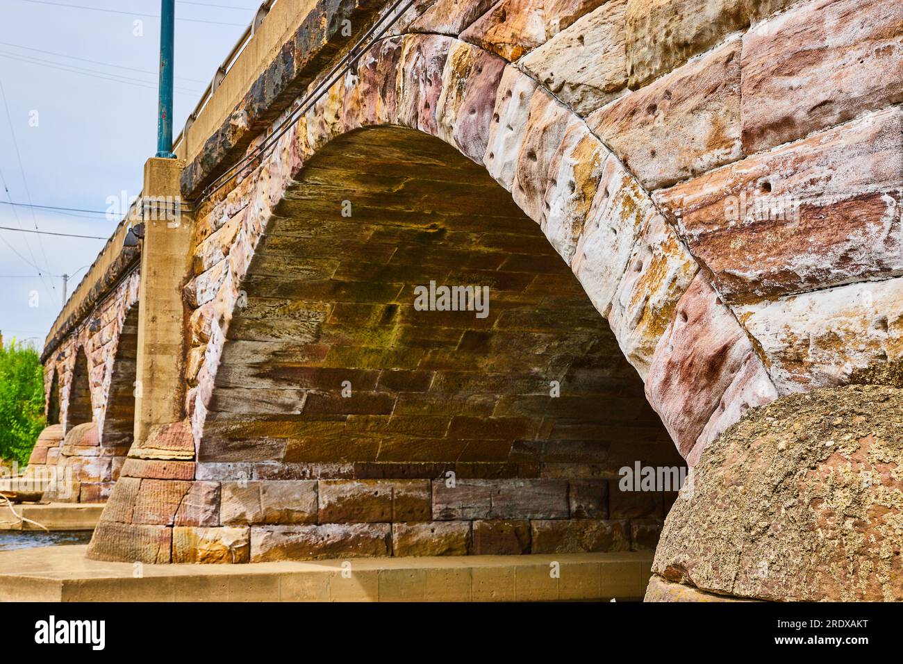 Stone bridge with golden and tan hues and large arches on underside ...
