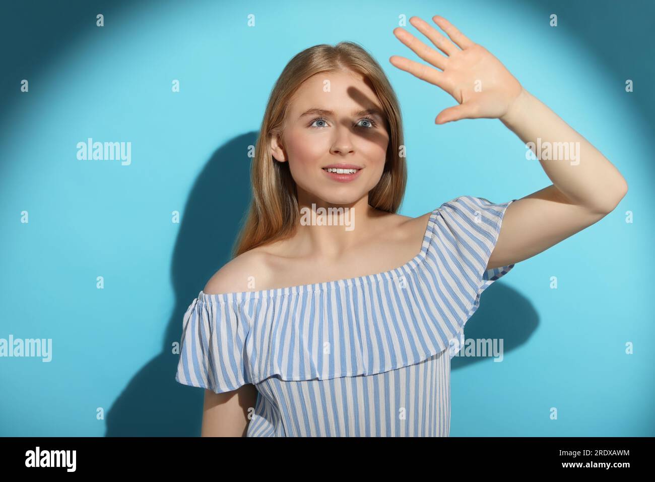 Beautiful young woman shading herself with hand from sunlight on light ...
