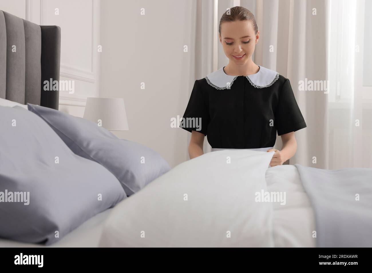 Young maid making bed in hotel room Stock Photo - Alamy