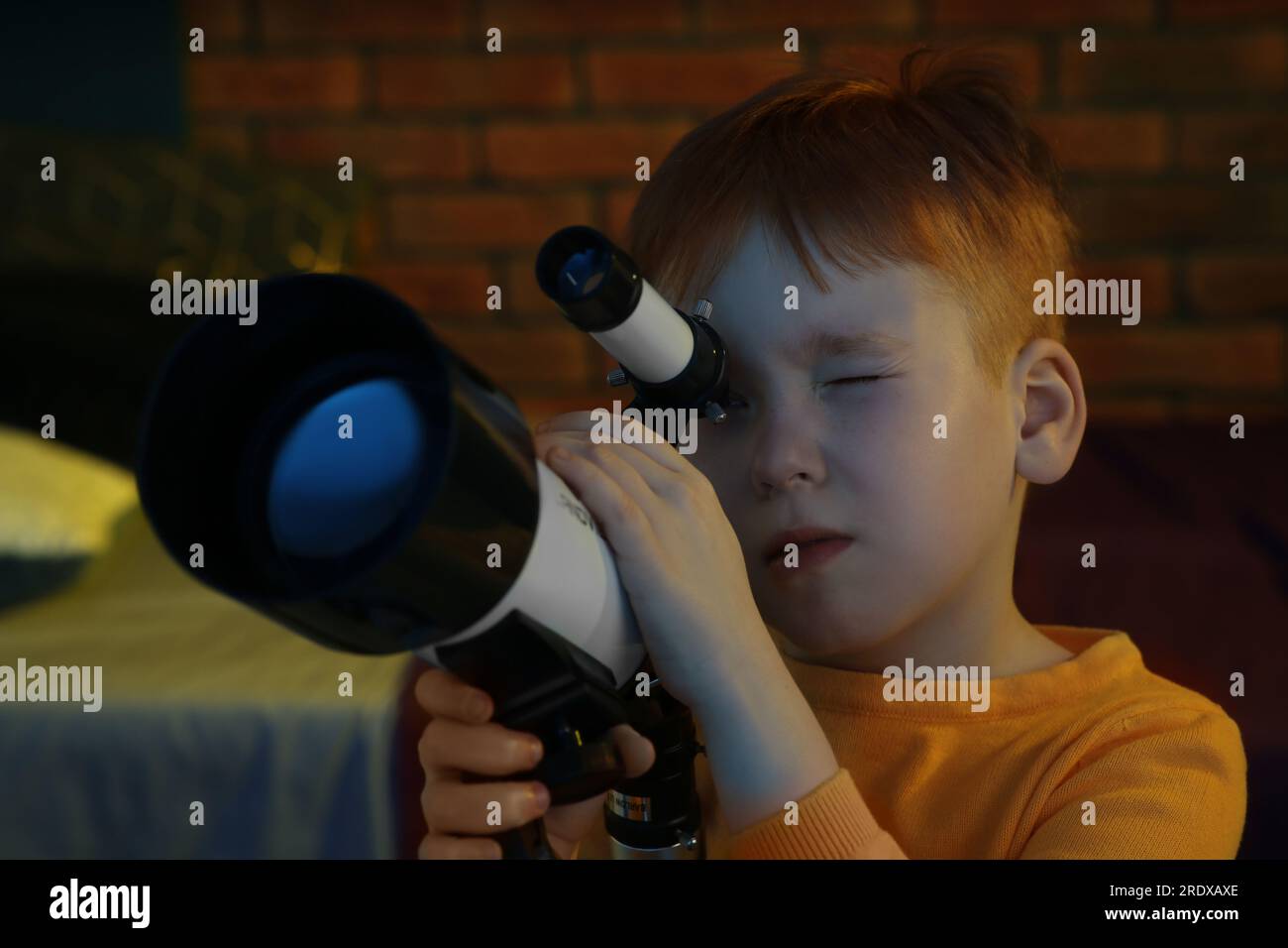 Little boy looking at stars through telescope in room Stock Photo - Alamy