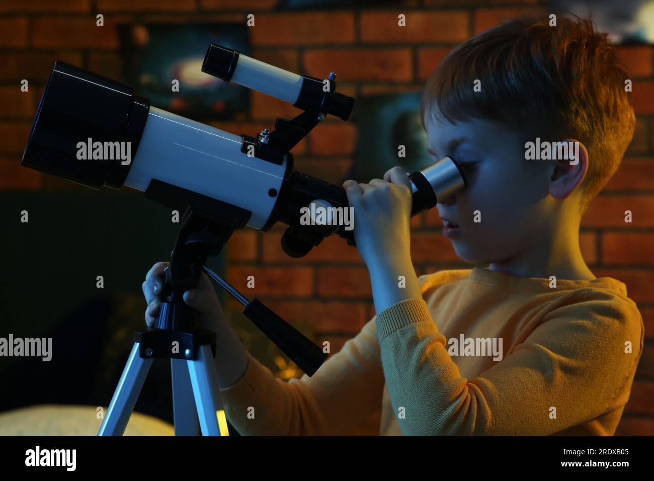 Little boy looking at stars through telescope in room Stock Photo - Alamy