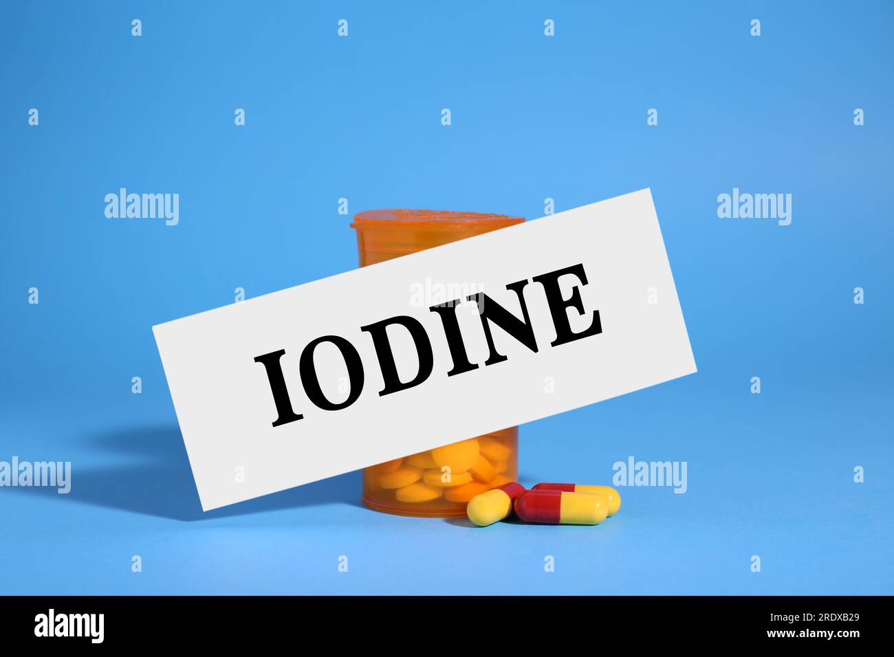 Paper note with word Iodine, bottle and pills on light blue background ...