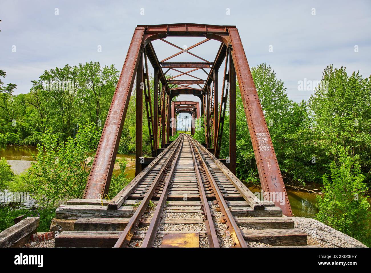 Summer shot of entrance to old train bridge with train tracks leading ...