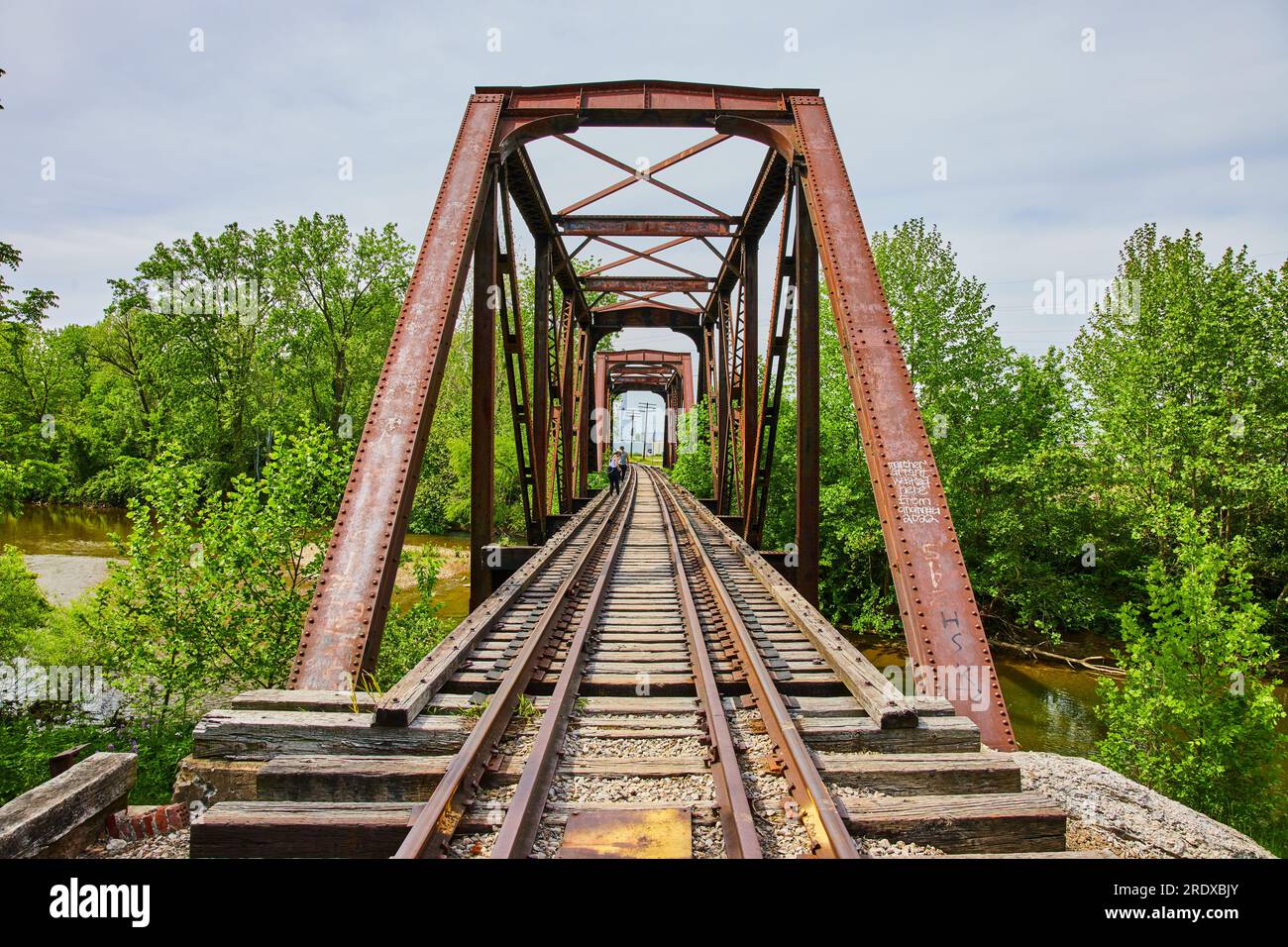 Summertime shot of entrance to railroad bridge with people on train ...