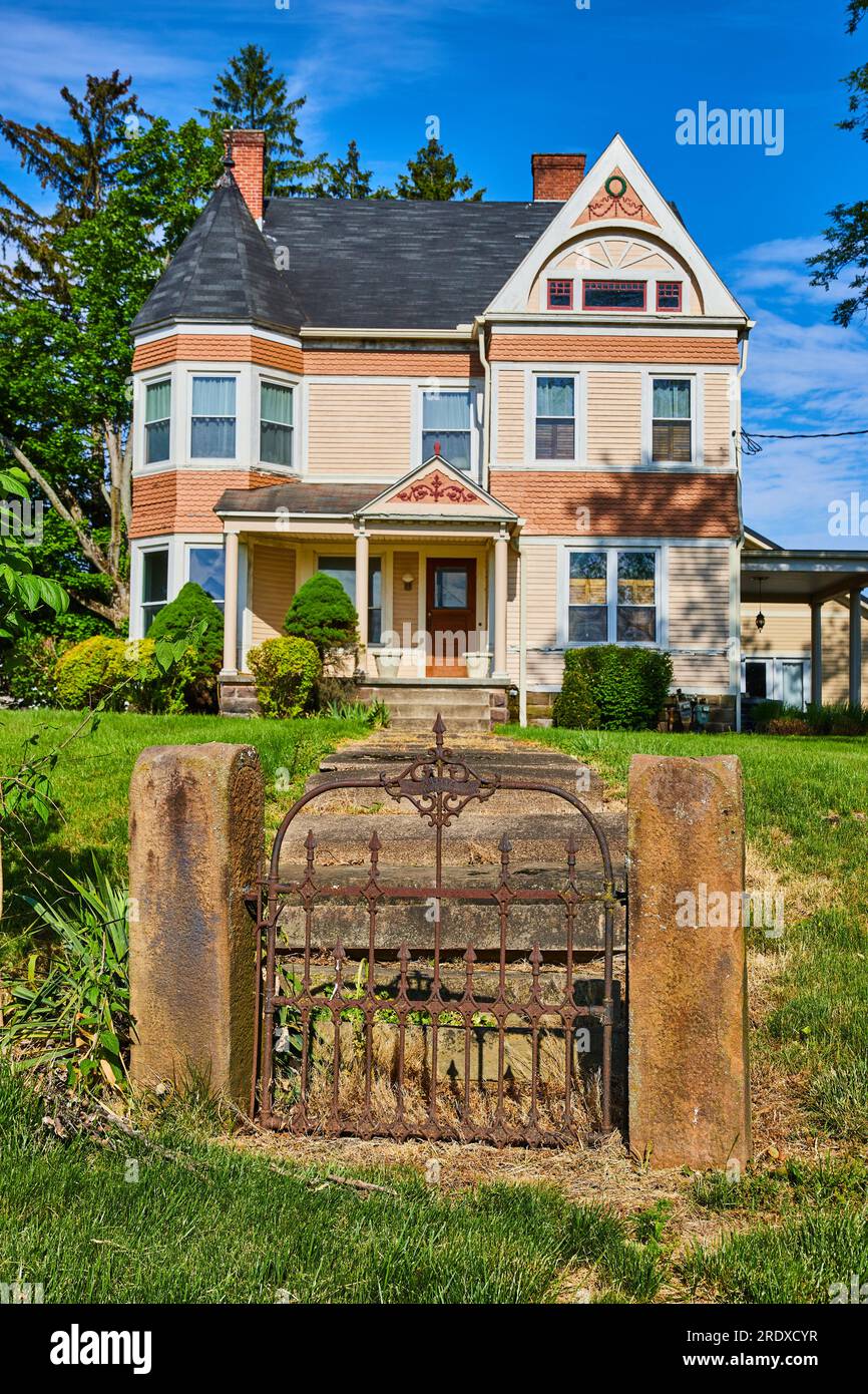 Rusting iron gate in front of old fashioned home on bright summer day ...