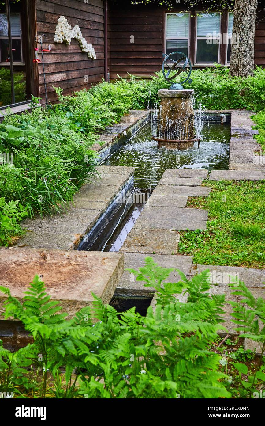 Peaceful water fountain with abstract sphere and water canal leading to ...