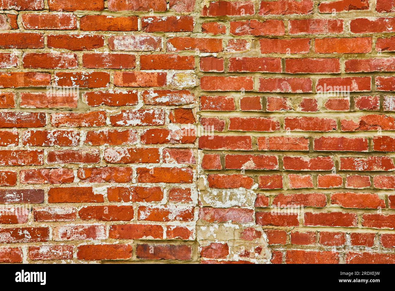 Red brick wall with crease down middle and splotches of white paint ...