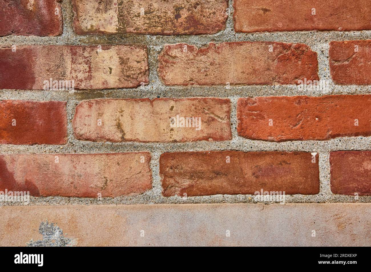 Background asset of grimy red brick wall with sliver of tan concrete at ...
