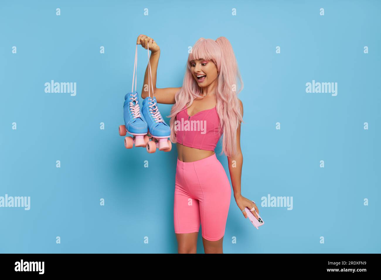 Slim girl in pink top and yoga pants with barbie hairstyle stands in ...